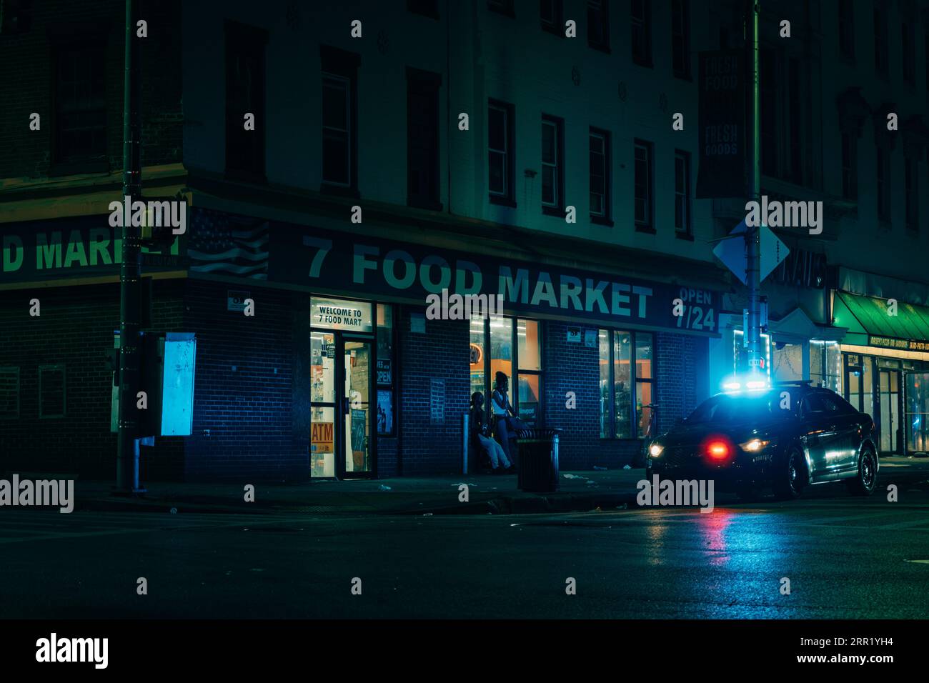 Police car with lights on outside of 7 Food Mart at night in Baltimore ...