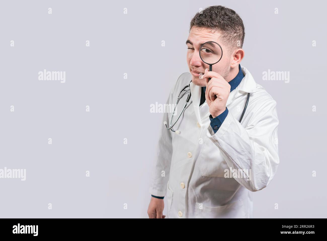 Doctor holding magnifying glass and looking at camera on isolated ...