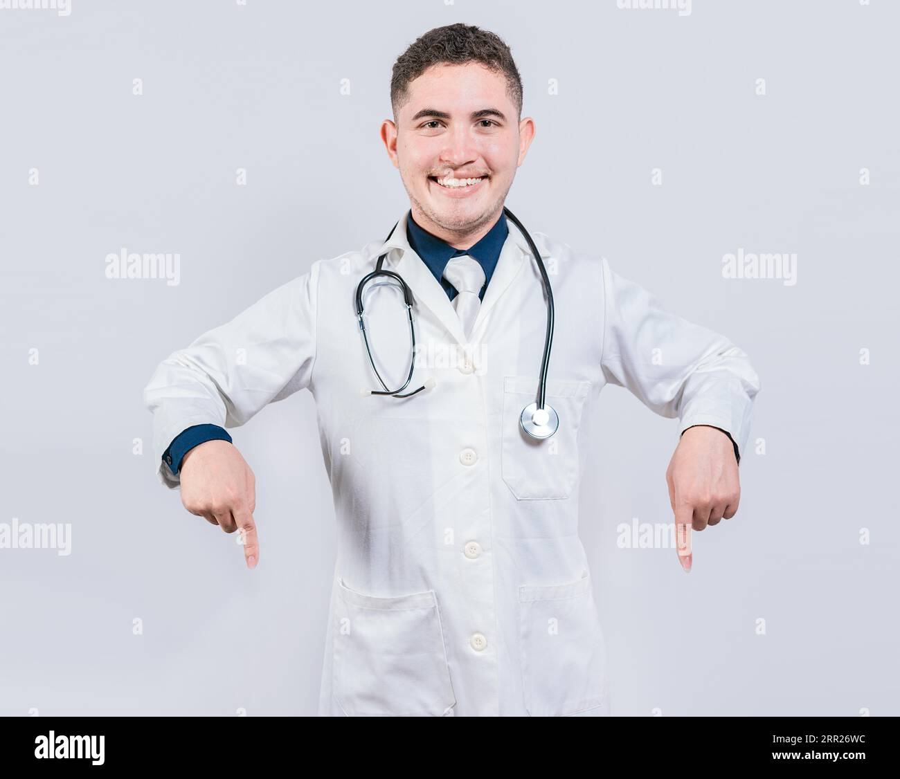 Young doctor pointing a promotion down. Happy doctor pointing fingers ...