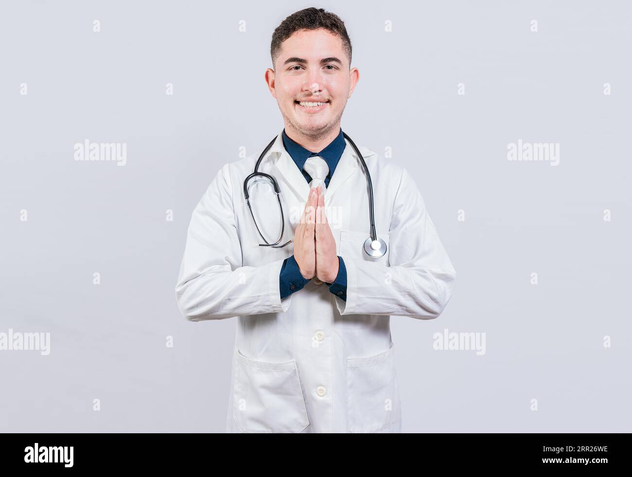 Smiling latin doctor with palms together isolated. Cheerful doctor ...