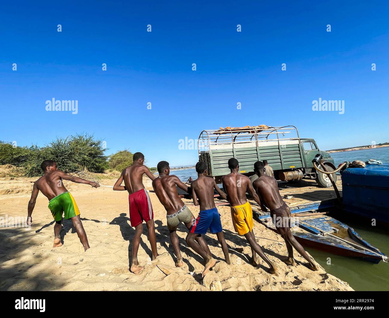 Madagascar, Tsiribihina river, young men tow barge on river Stock Photo ...