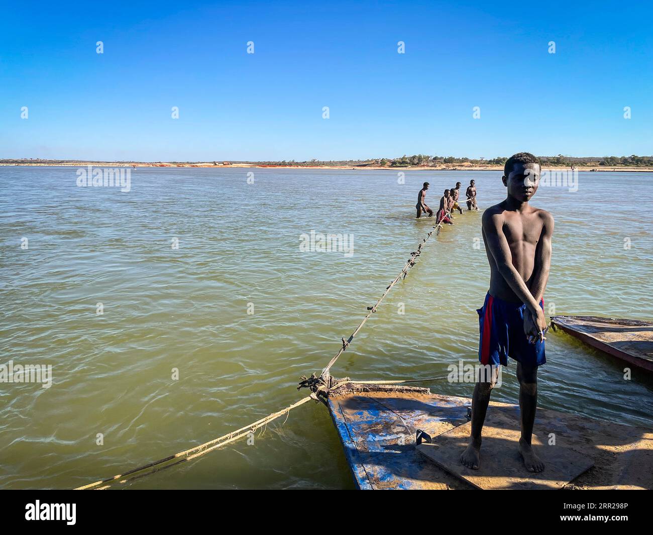 Madagascar, Tsiribihina river, young men tow barge on river Stock Photo ...