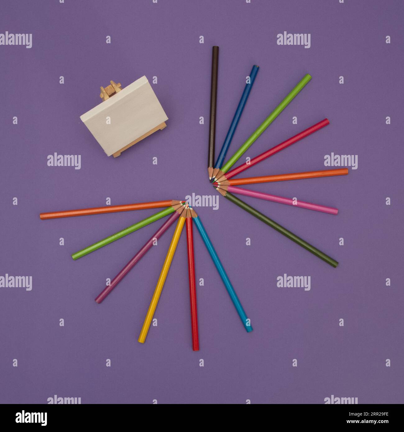 Wooden crayons of various colors on a purple background with canvas for ...