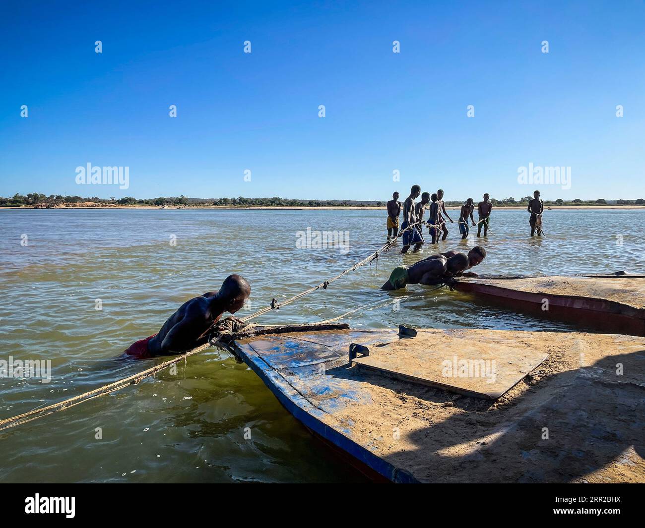 Madagascar, Tsiribihina river, young men tow barge on river Stock Photo ...
