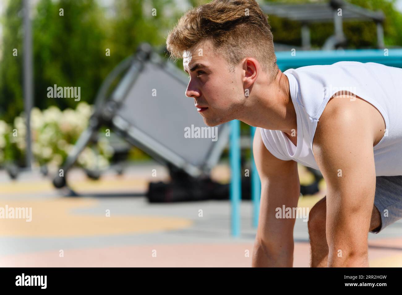 Shot of a man running from a crouched position against an sports ground ...