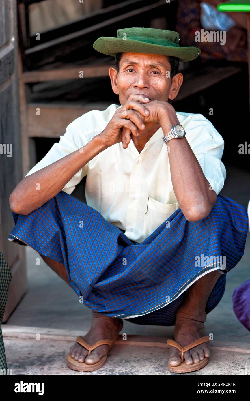 Man squatting in front of his house, Myanmar, Burma, Burma, Southeast ...