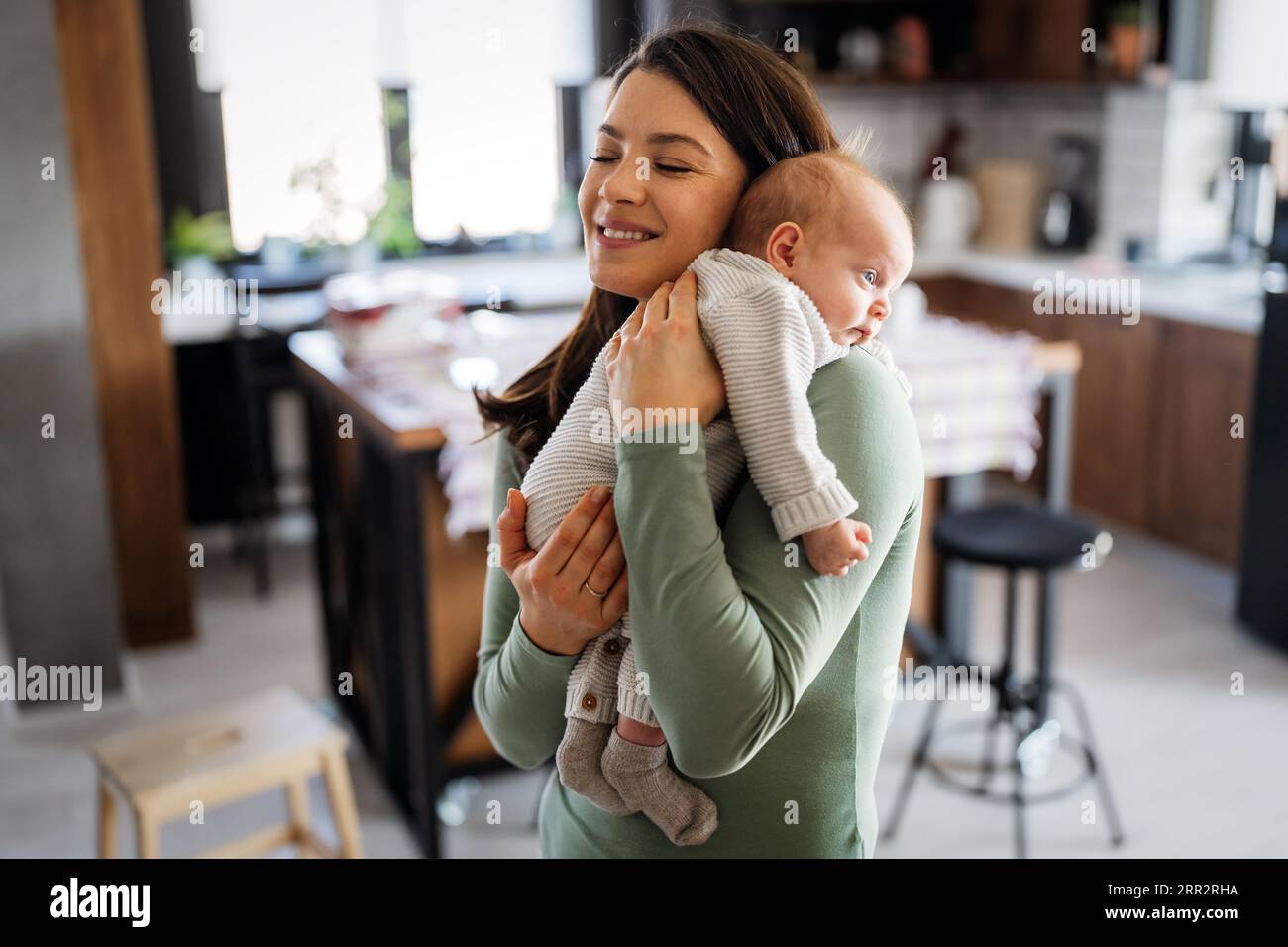 Loving mother carying of her newborn baby at home. Family parenting ...