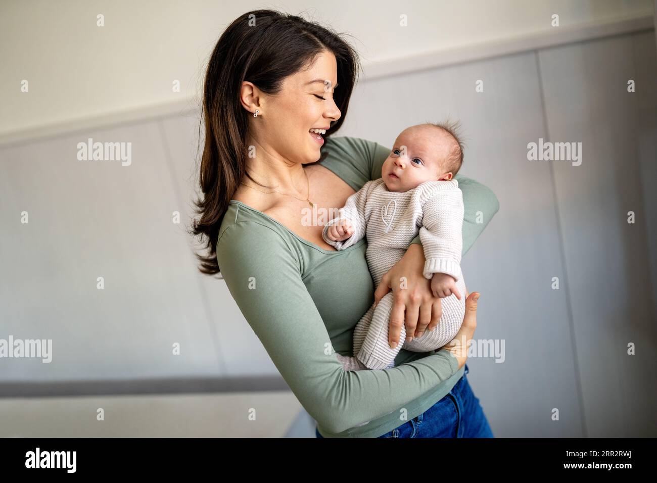 Loving mother carying of her newborn baby at home. Family parenting ...