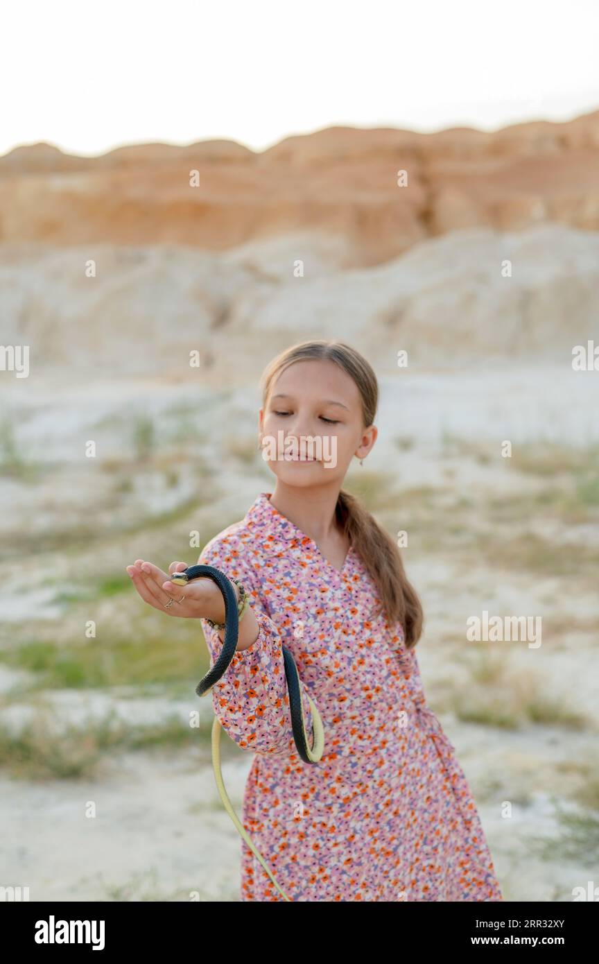 A teenage girl plays with a snake, holding it in her hands. Children ...