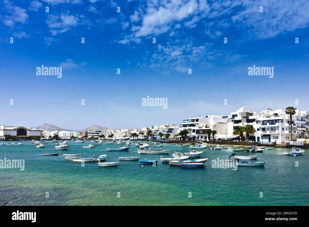 White buildings against blue sky and small fisher boats at the laguna ...