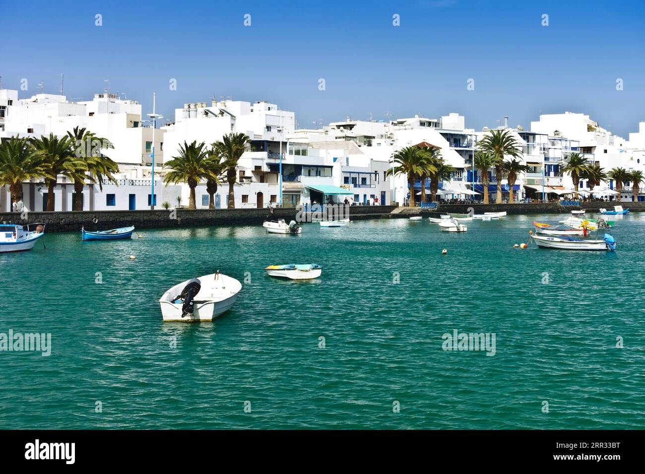 White buildings against blue sky and small fisher boats at the laguna ...