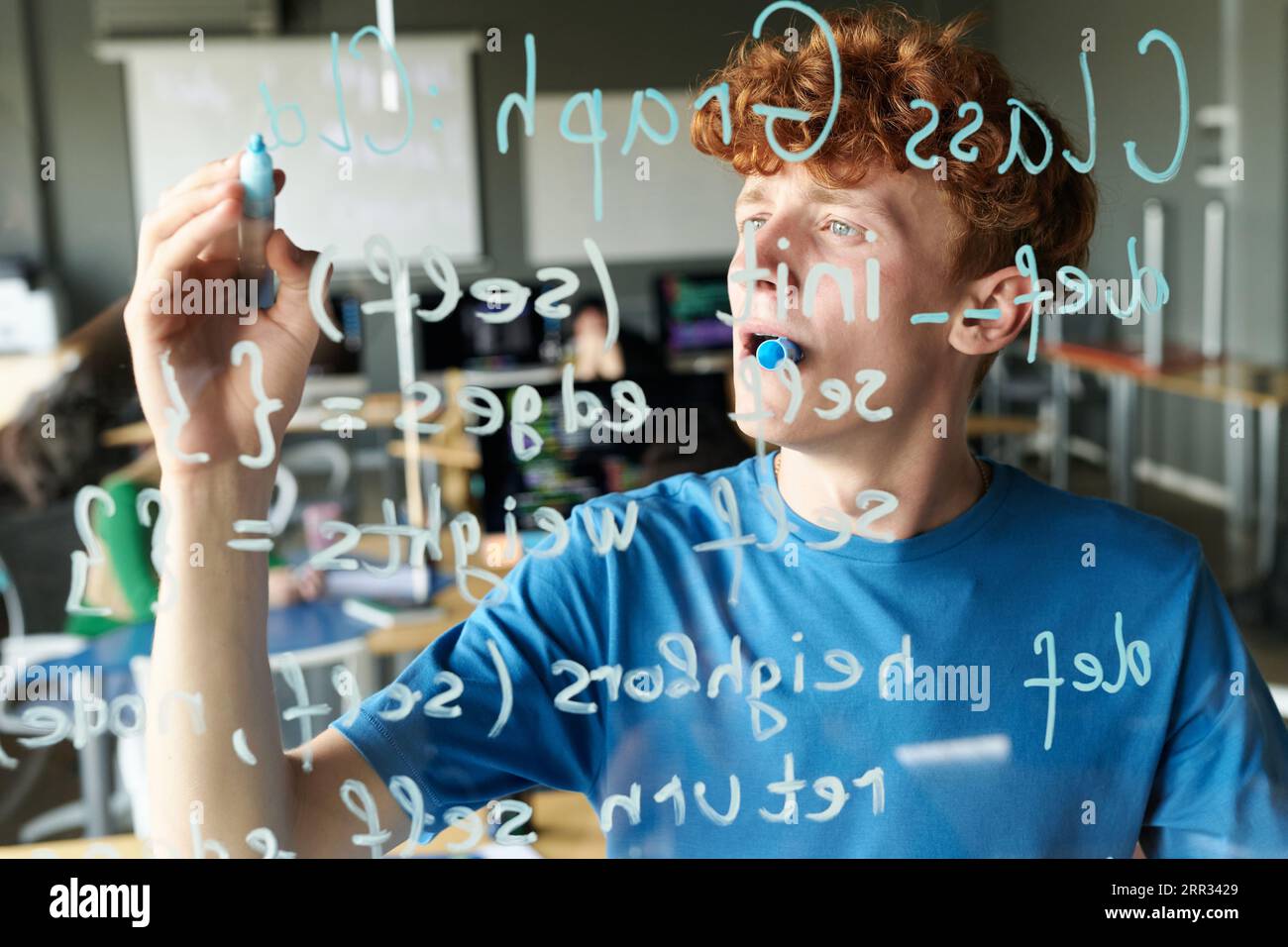 Student writing computer codes on glass wall during IT lesson in the ...