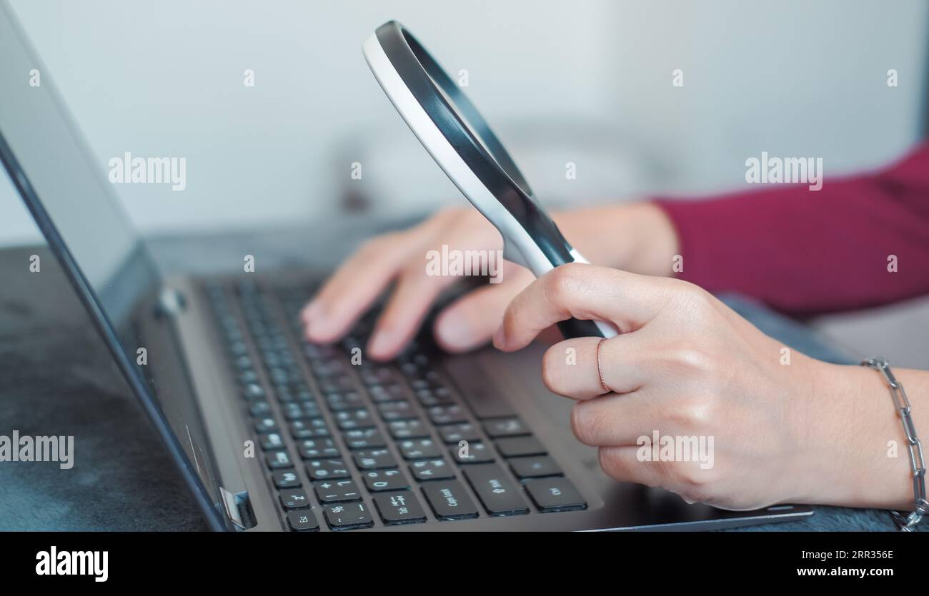 woman doing work and using a magnifying glass to look at data Suitable ...