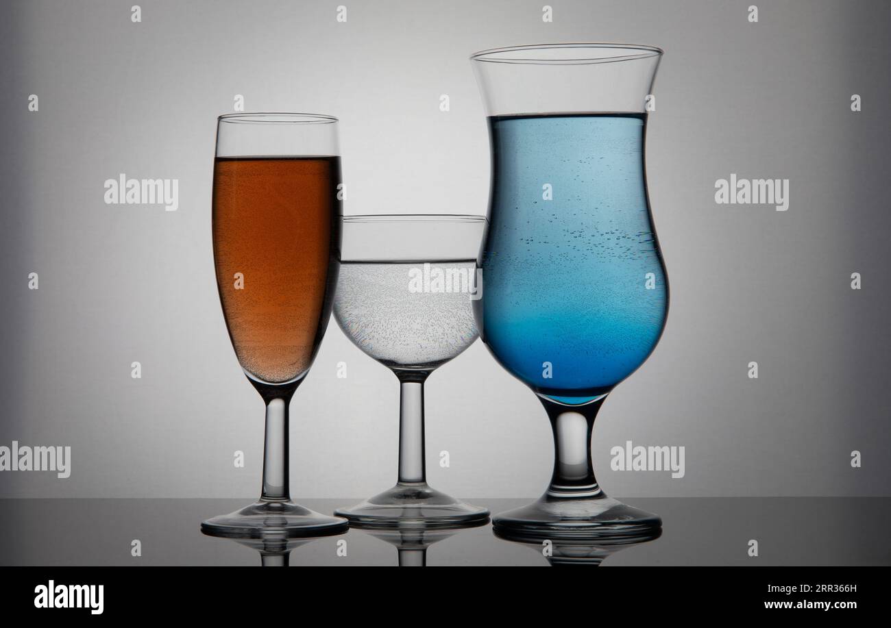 A still life of three glasses filled with different coloured liquid ...