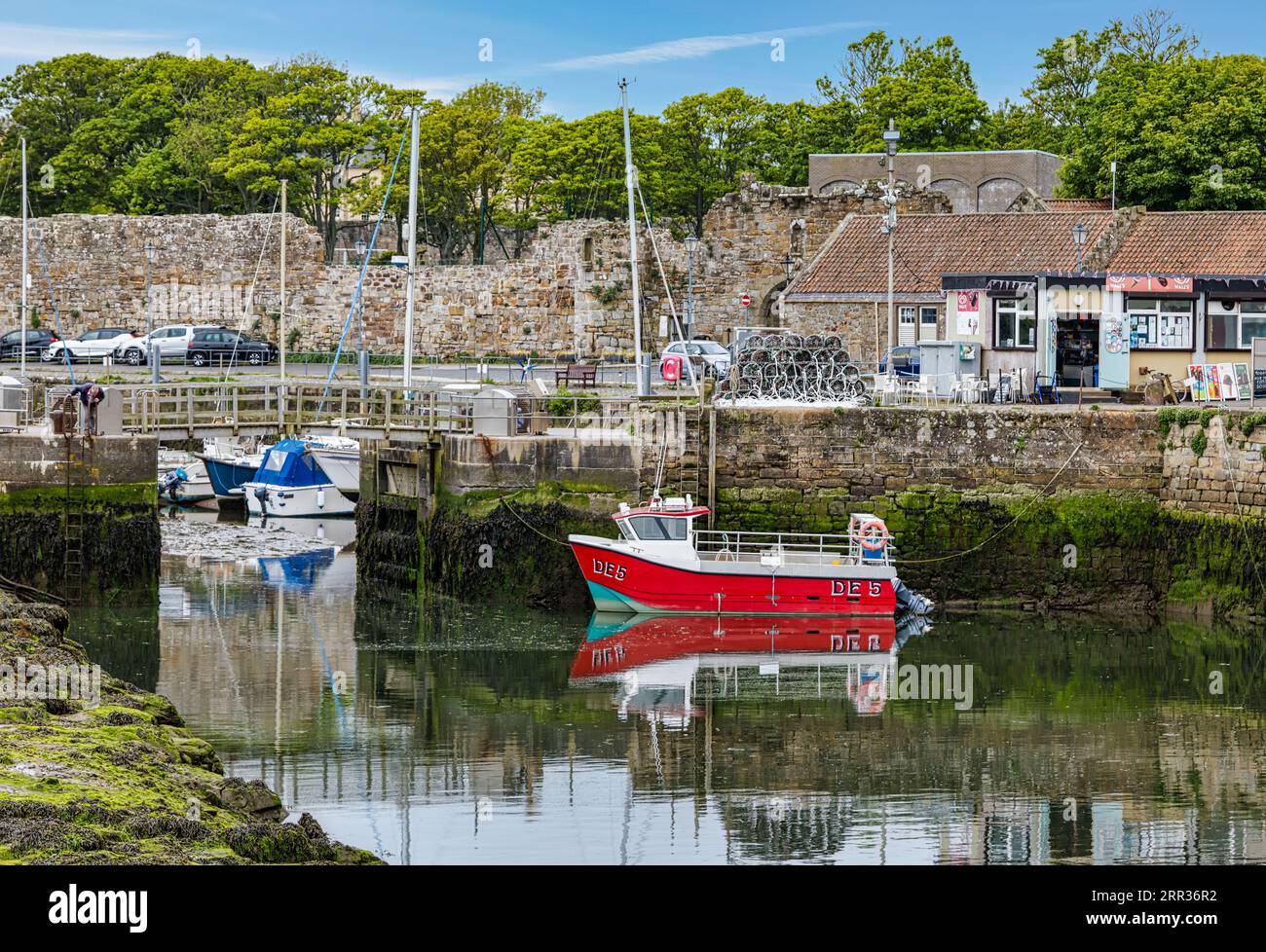 Small harbour with fishing boat reflected in water at low tide, St ...