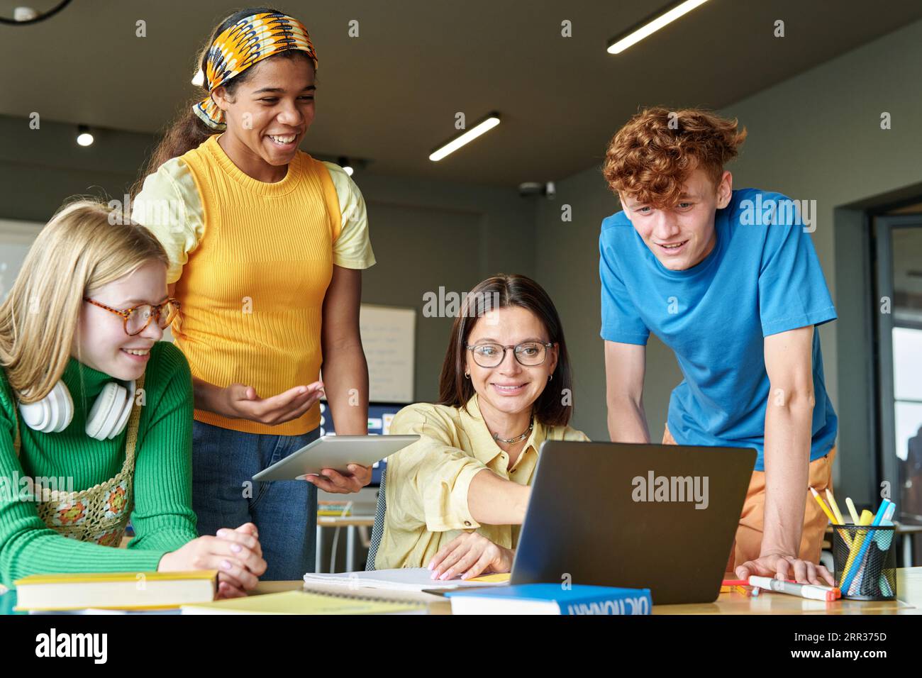 Group of students discussing software with teacher at IT lesson in the ...
