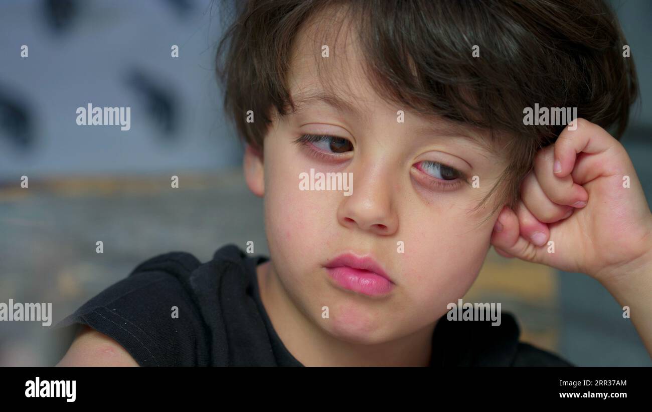 Close-up child face with bored expression. Pensive small boy struggles ...