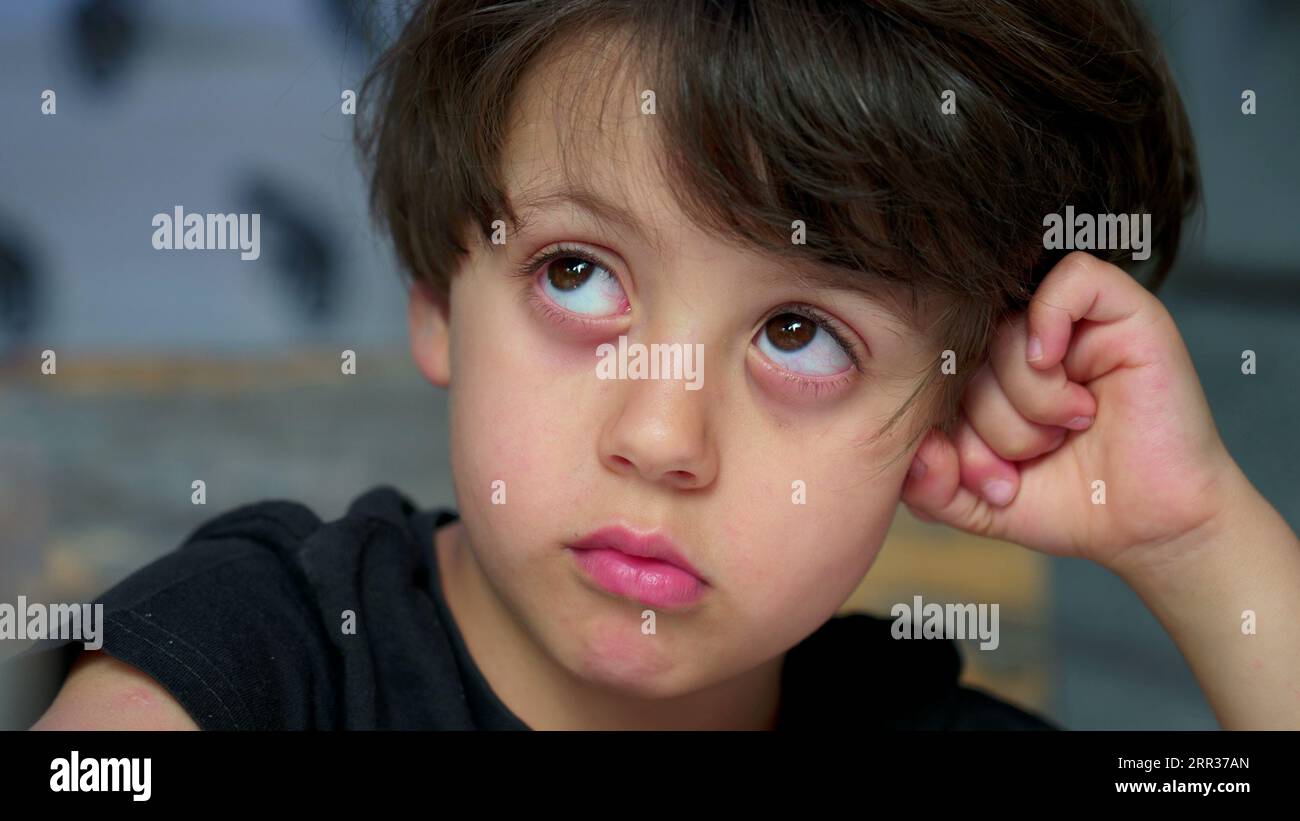 Close-up child face with bored expression. Pensive small boy struggles ...