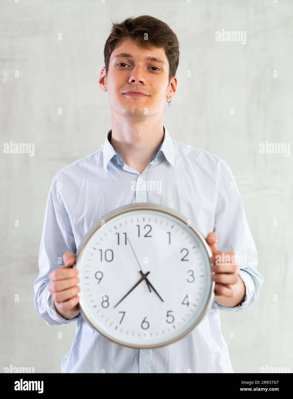 Young guy posing with clock in studio Stock Photo - Alamy
