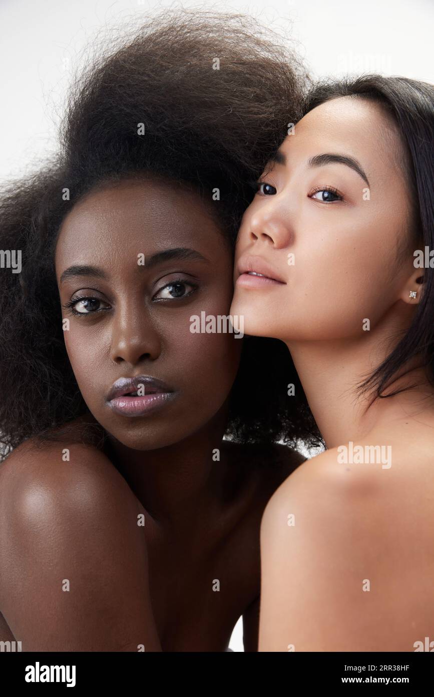 Two beautiful young women, african and asian with well-kept skin ...