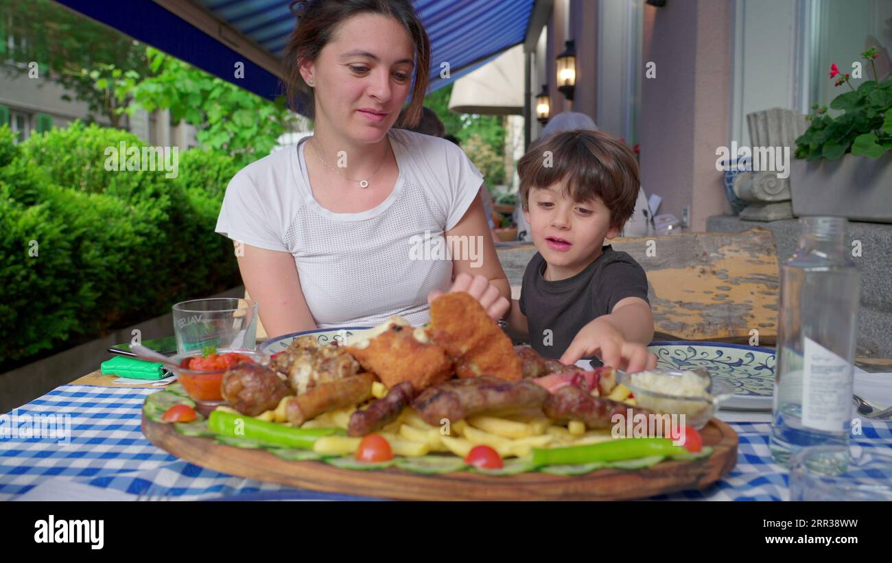 Mother and child eating an abundant Greek plate of food at restaurant ...