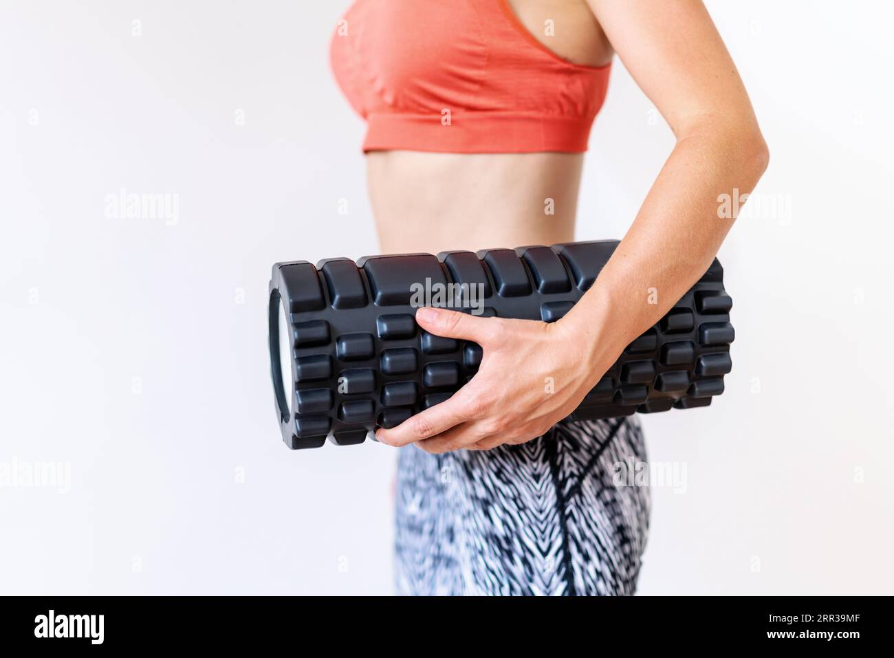 Studio shot size view a foam roller in hand of female slim athlete on white background Stock ...