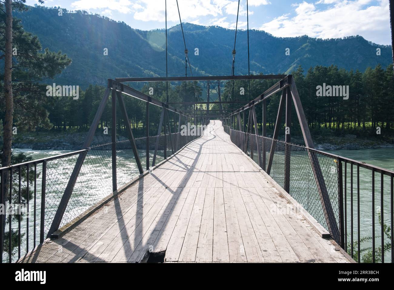 A wooden bridge with metal supports across a raging river Stock Photo ...