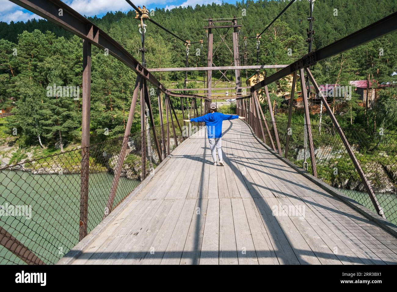 A wooden bridge with metal supports across a raging river Stock Photo ...