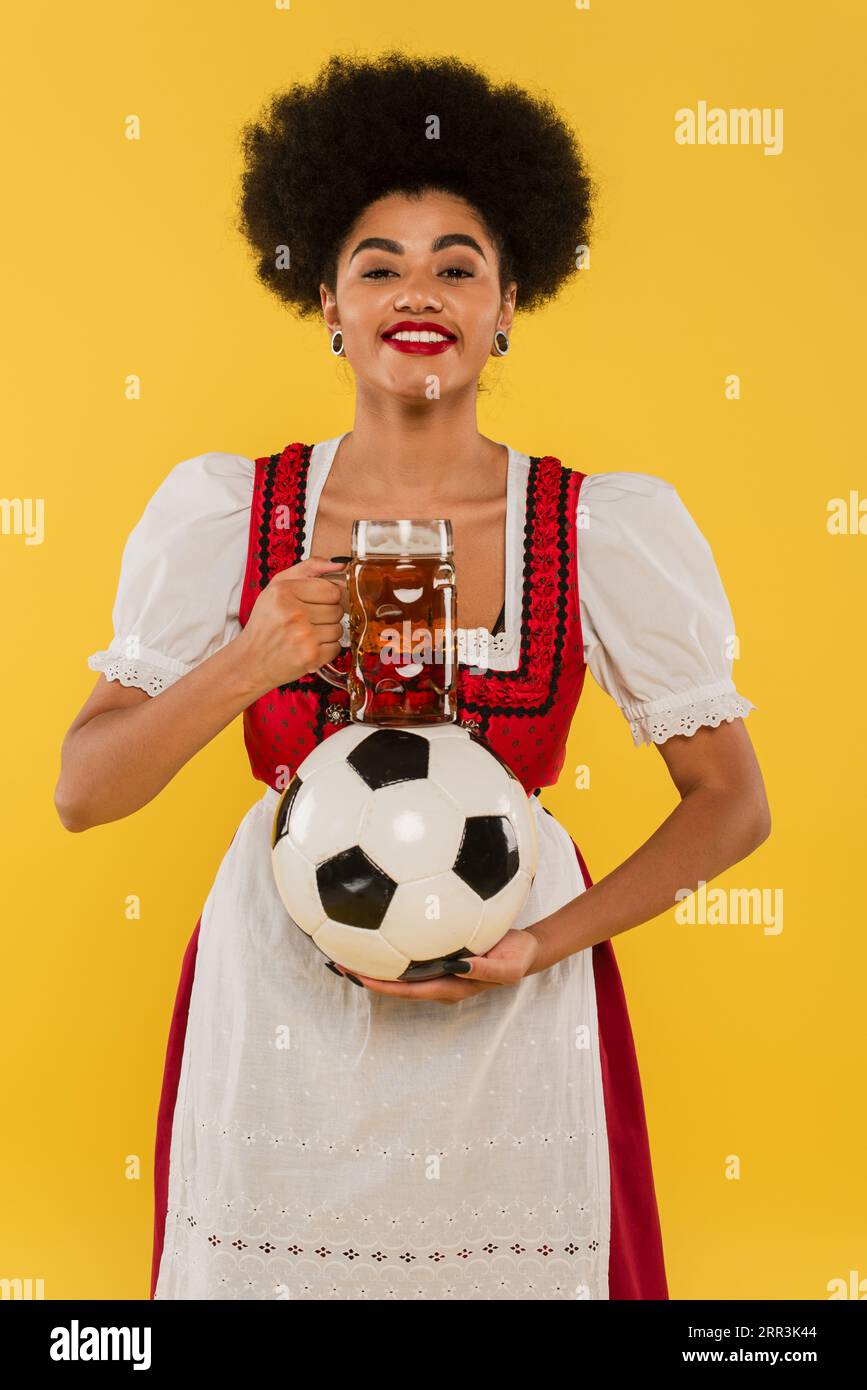 happy african american bavarian waitress with beer mug and soccer ball ...