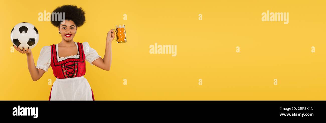 happy african american bavarian waitress in dirndl with beer mug and ...