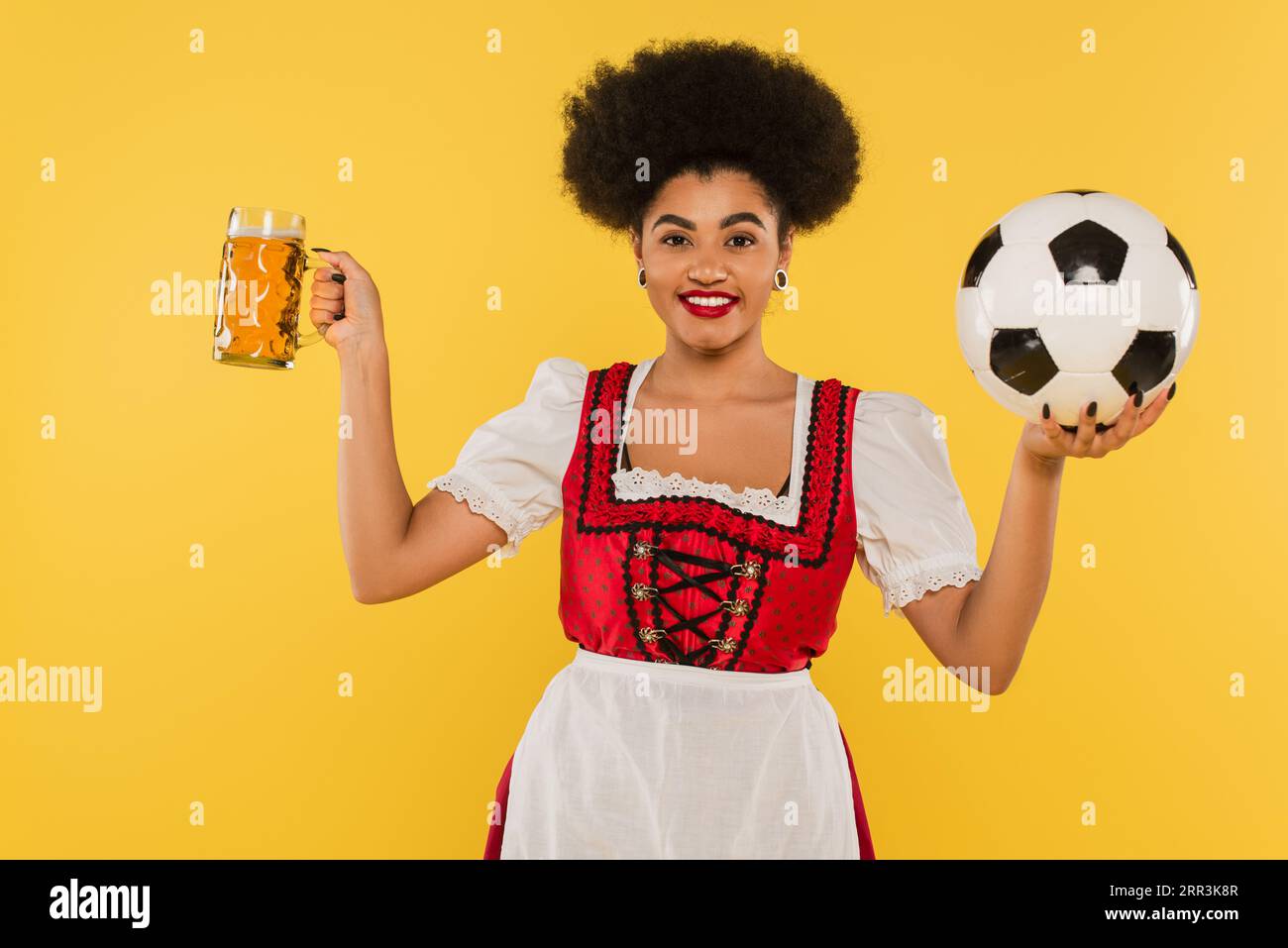 cheerful african american bavarian waitress in dirndl holding beer mug ...