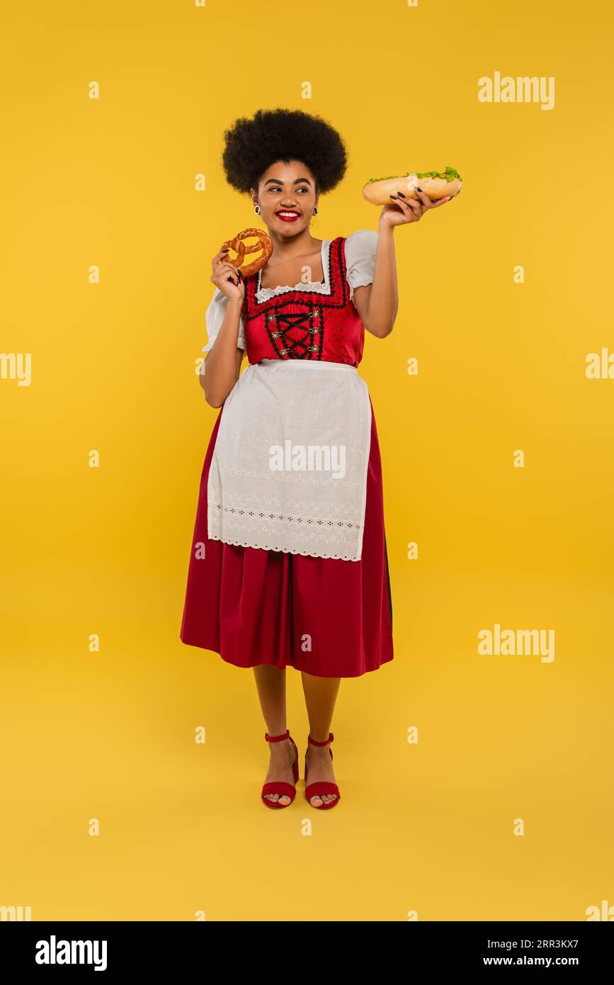 pretty, happy african american bavarian waitress in dirndl posing with ...