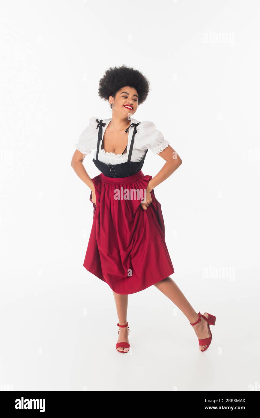 overjoyed african american oktoberfest waitress in traditional bavarian ...