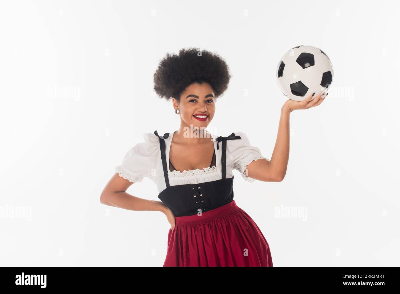 smiling african american bavarian waitress in dirndl with soccer ball ...