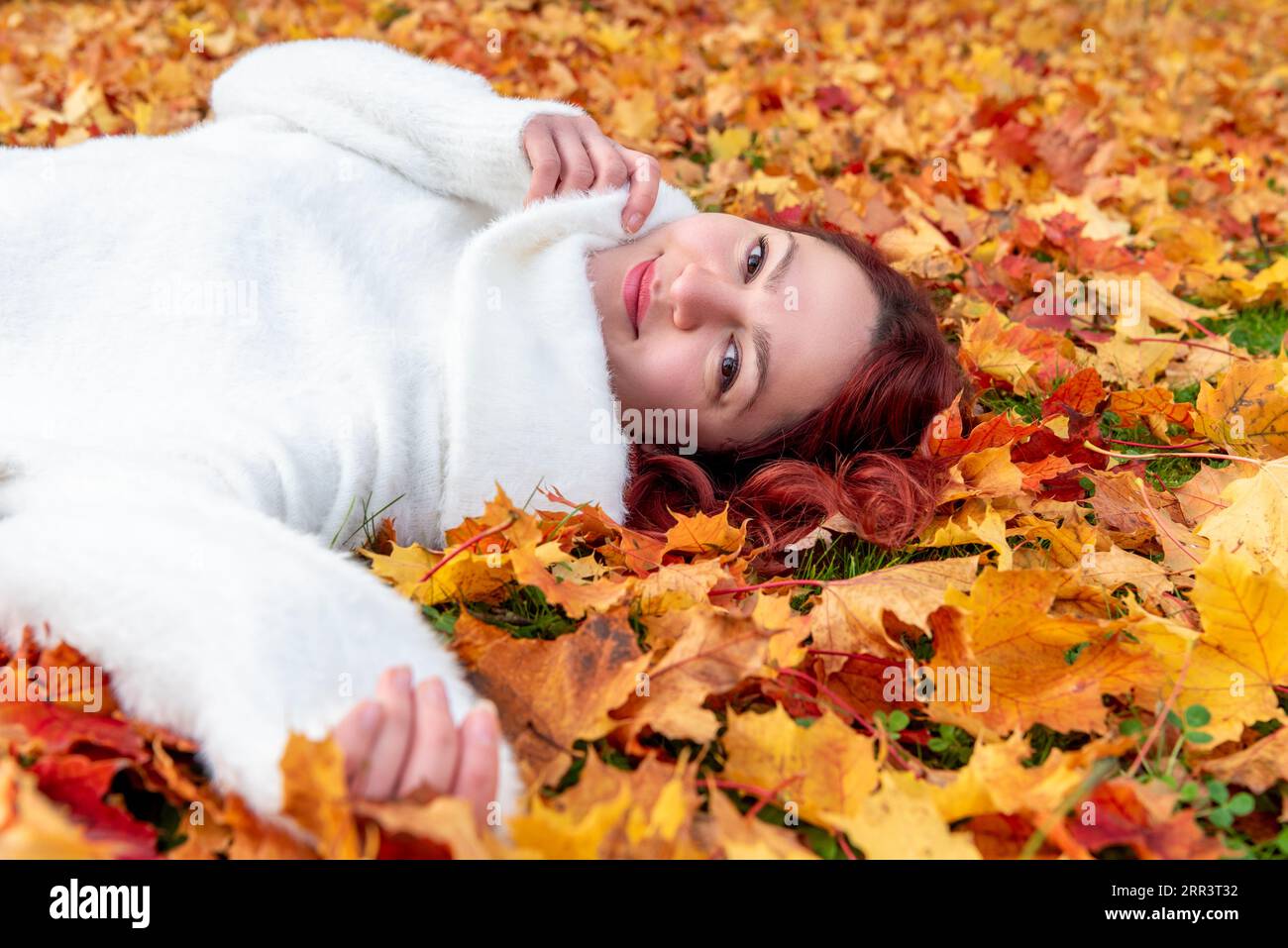 Autumn scenery with a woman lying on the ground surrounded by colorful ...