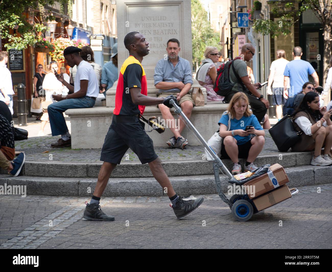 DHL parcel worker with trolley in Seven Dials London Stock Photo - Alamy