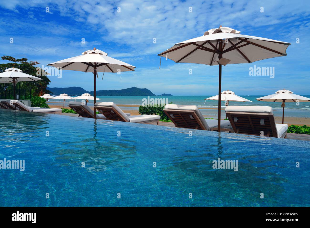 White umbrellas reflecting in an infinity pool overlooking the sea ...