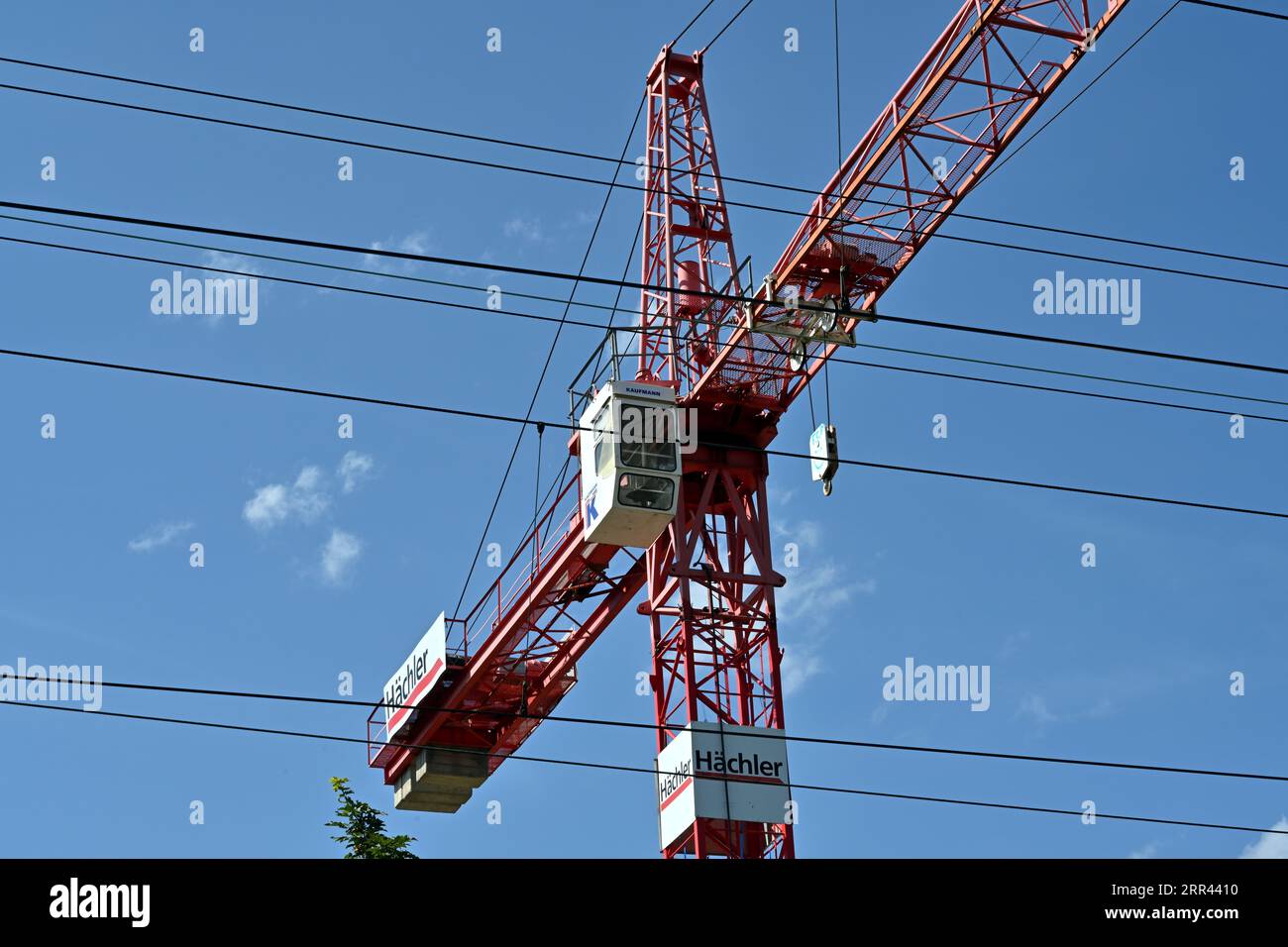 A tower industrial crane of red color with a stretched arm and a white ...