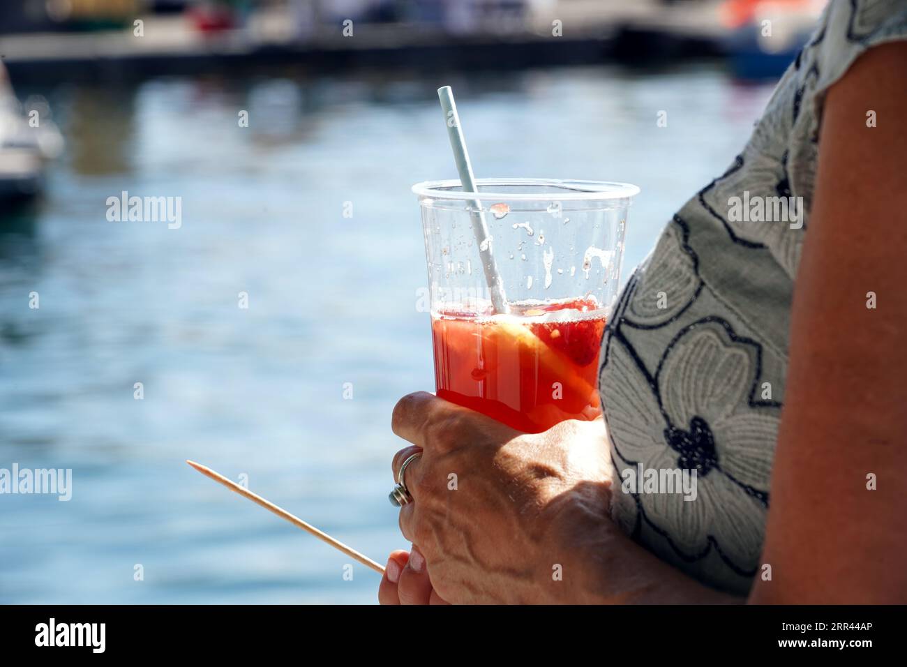 Plastic glass with strawberry drink and paper straw inside holding by ...