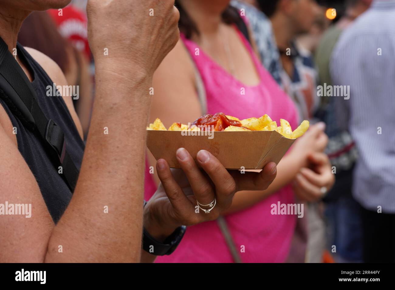 Standing woman holding a paper tray with French frites and ketchup ...