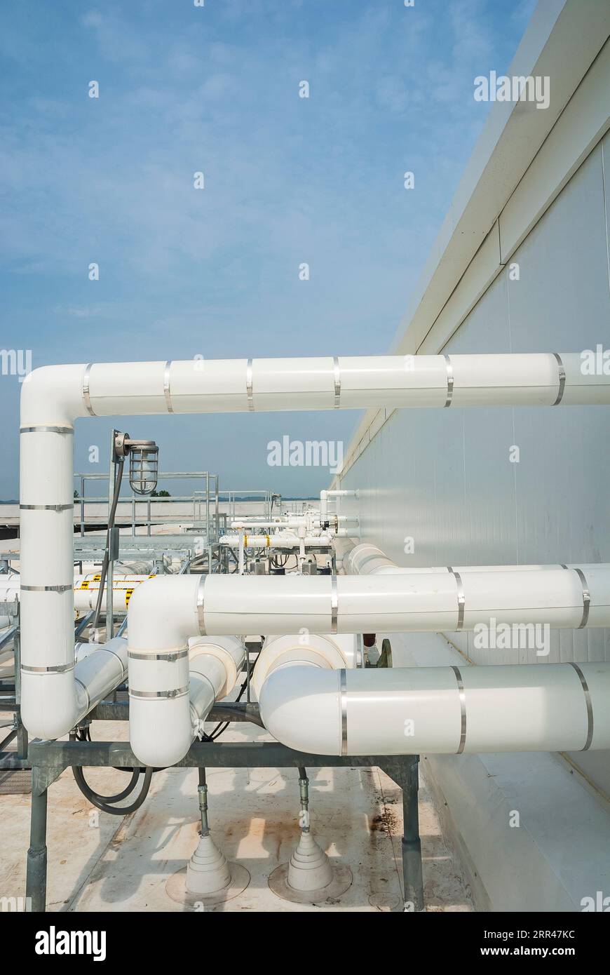 White insulated piping mounted on roof of cold storage facility, for ...