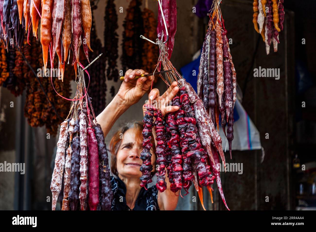 A saleswoman cuts off sticks from Tchurchela. Tchurtchela (ჩურჩხელა) is ...