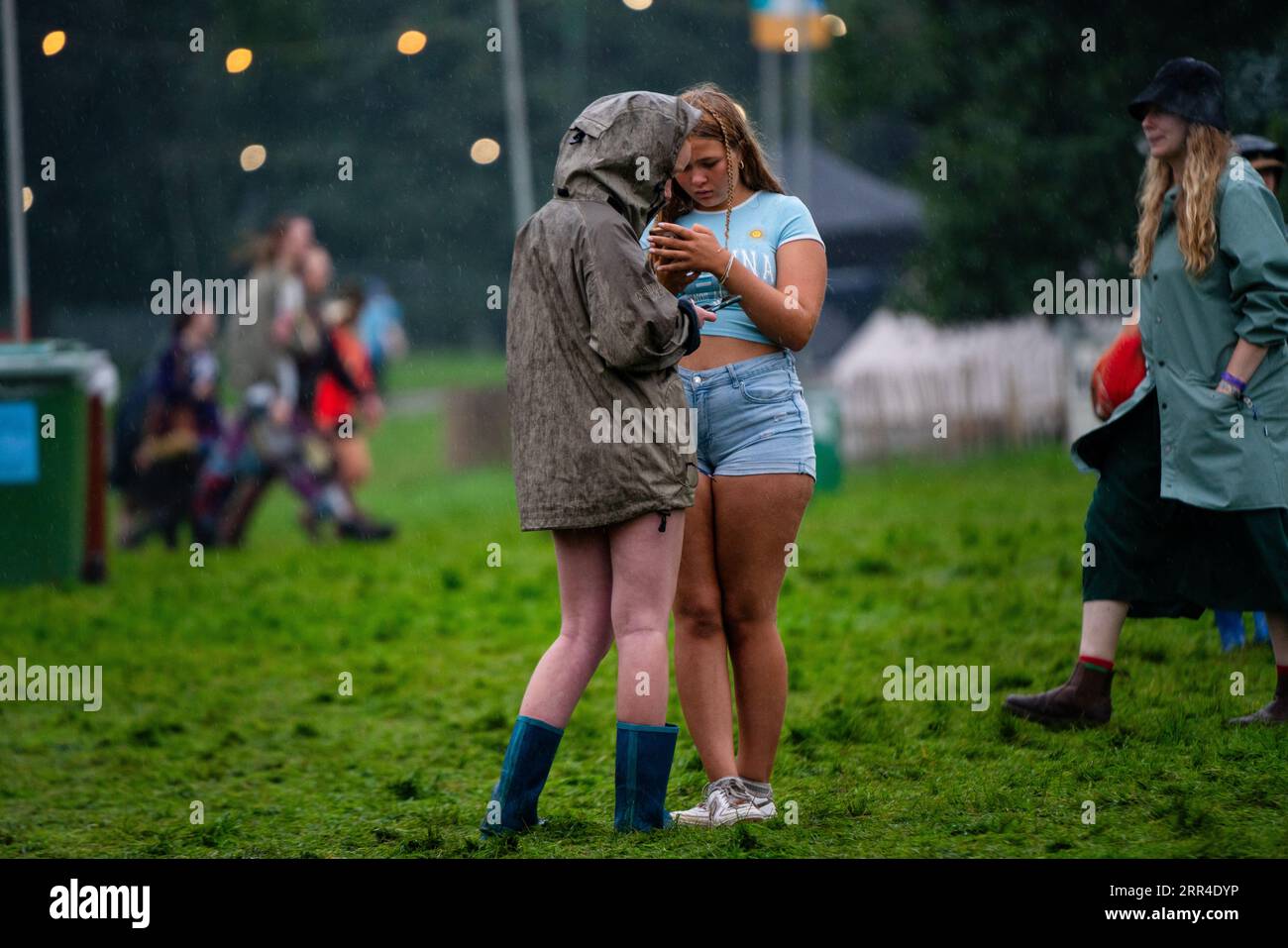 Two teen girls teenagers in the rainstorm rain and mud. Green Man ...