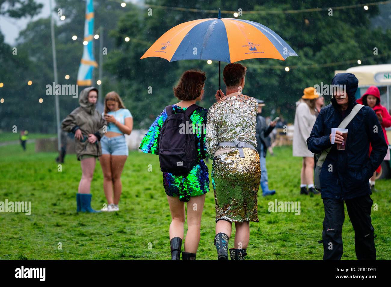 A glamorous glitter couple under an umbrella in the rainstorm rain and ...