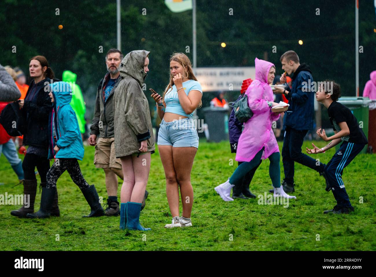 Two teen girls teenagers in the rainstorm rain and mud. Green Man ...