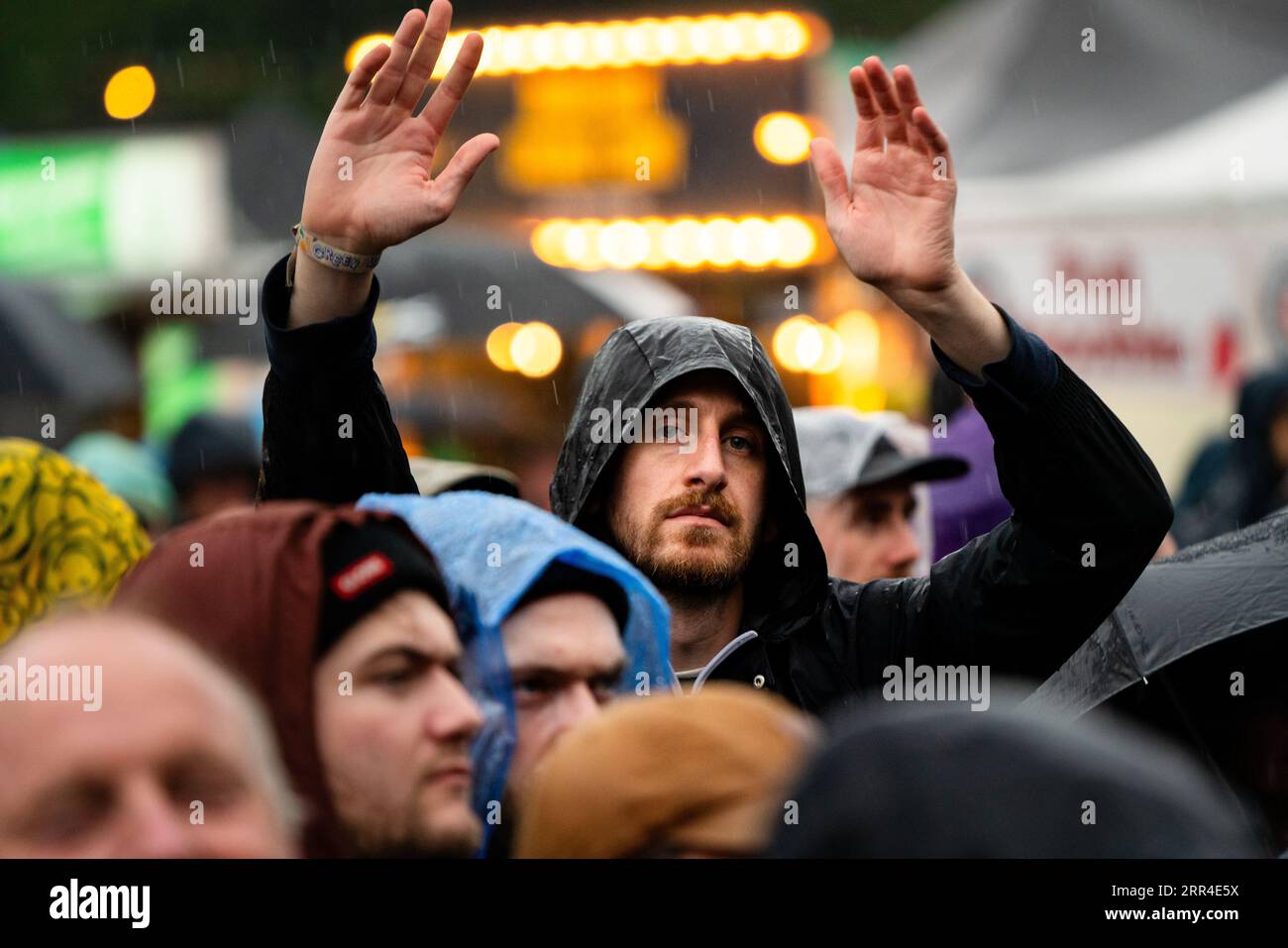 A man in wets cheering at the stage in the rainstorm rain and mud ...