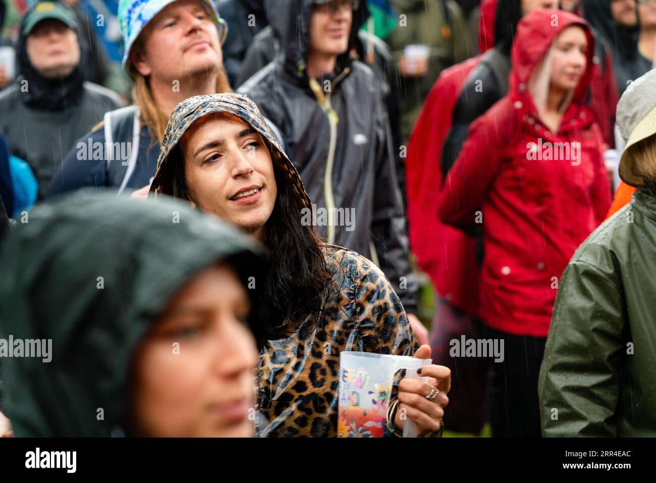 A woman in a leopard print raincoat with a beer in the rainstorm rain ...