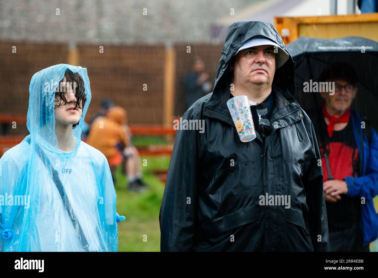 Teenage boy in a disposable rain poncho and a man with a beer glass in ...