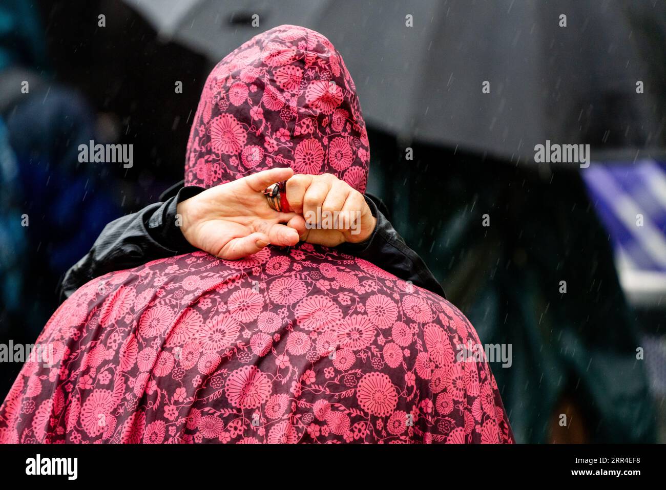 A faceless romantic couple dancing in rain clothes in the rain. Green ...