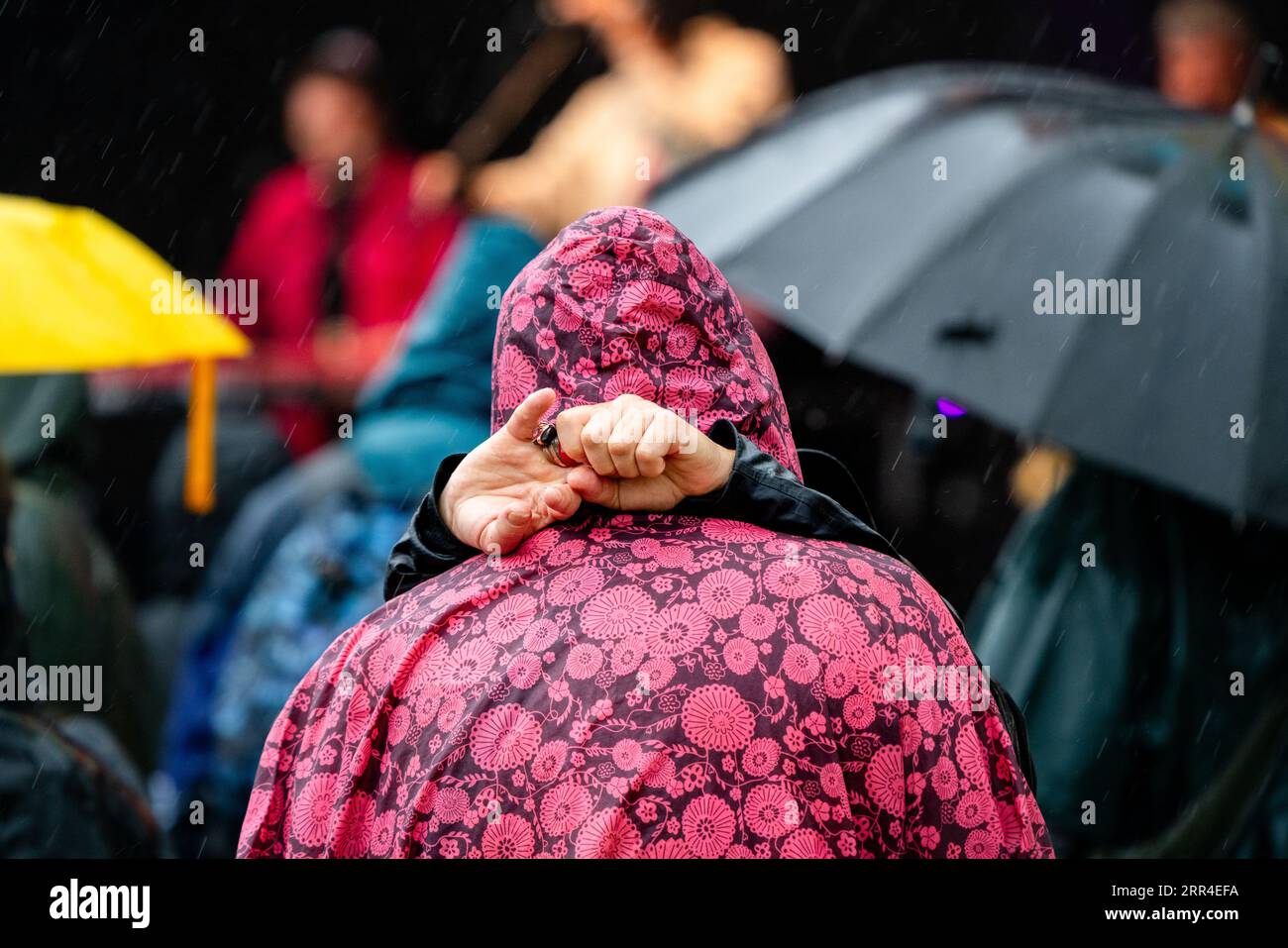 A faceless romantic couple dancing in rain clothes in the rain. Green ...